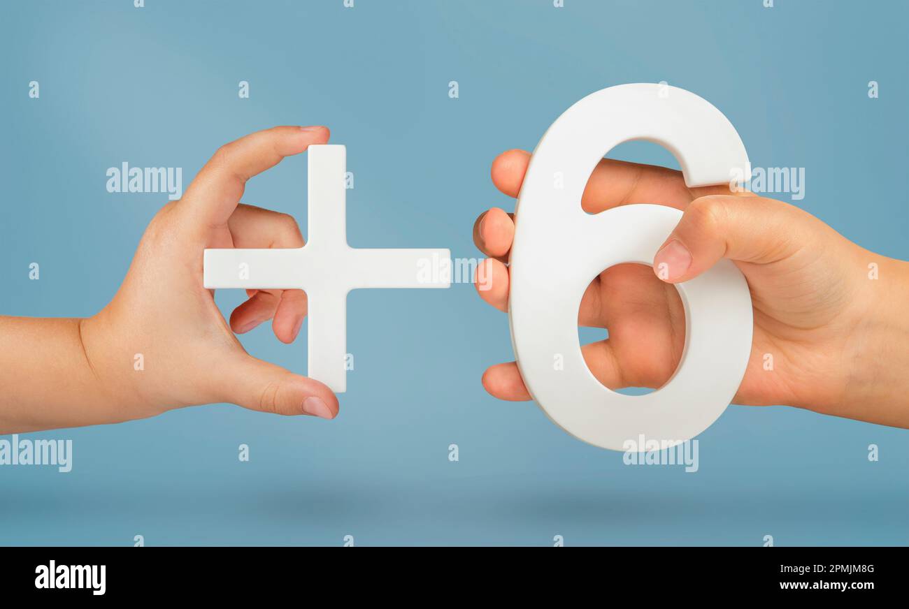 The number six and the plus symbol in the hands of a child on a blue ...
