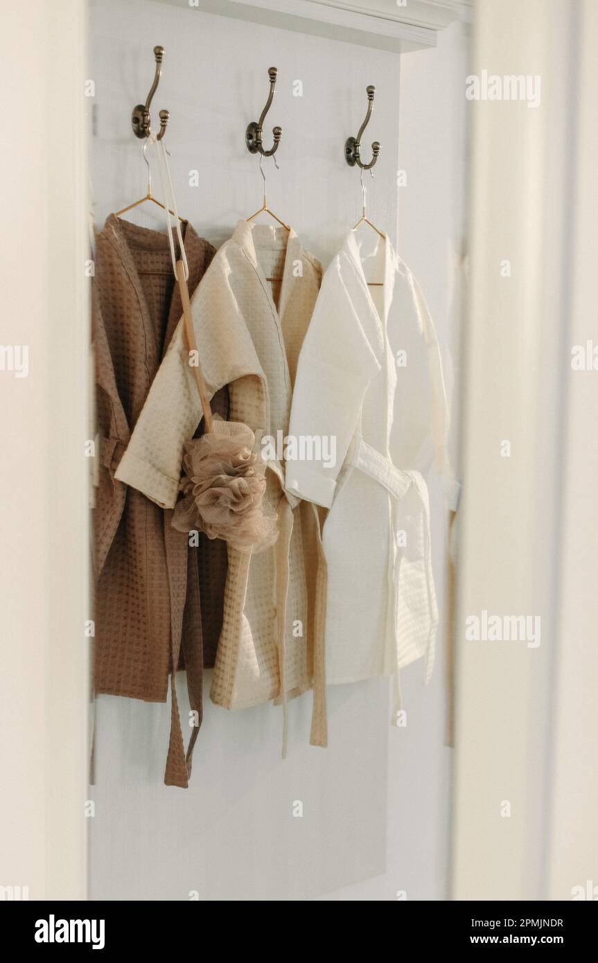 Three linen robes of different colors hang on a hanger in the bathroom ...