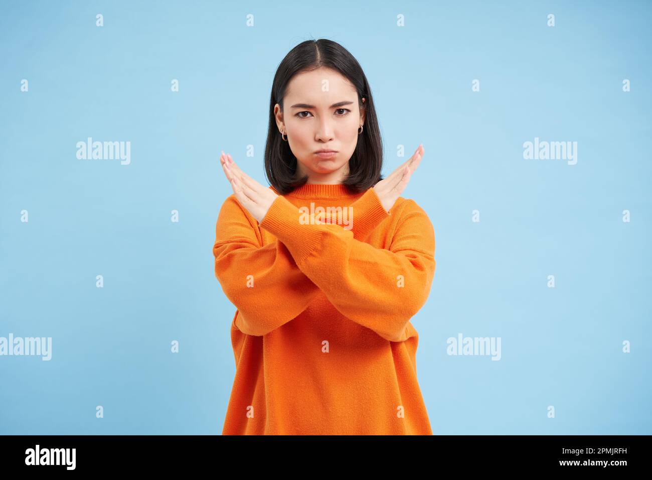 Image of serious korean woman shows cross hands gesture, stop sign ...