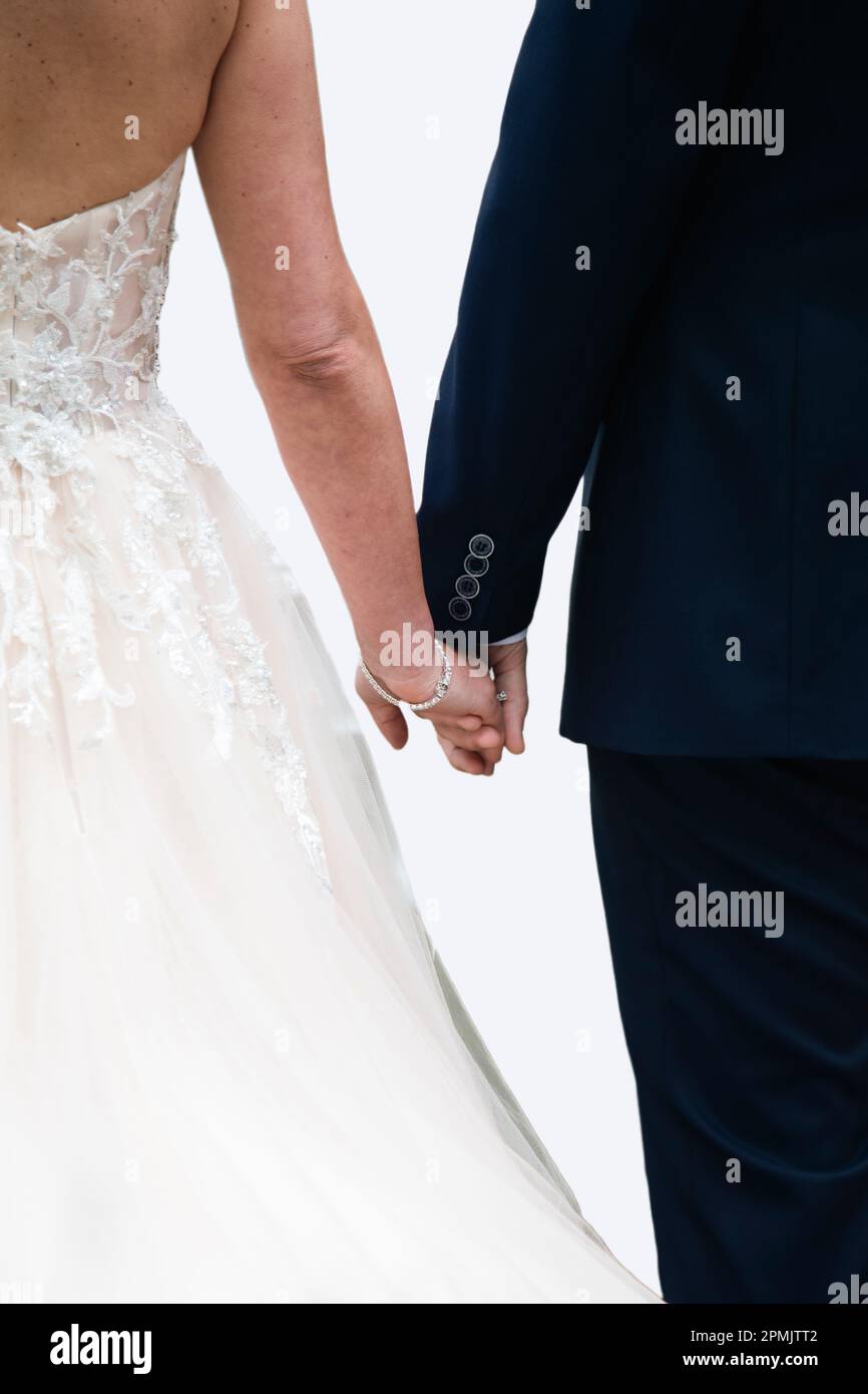 A happy newlywed couple join hands in a symbol of love and commitment ...