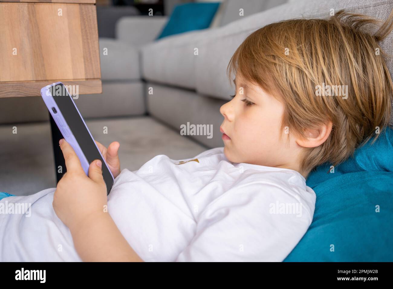 Close up cute little boy using smartphone, looking at screen, curious ...