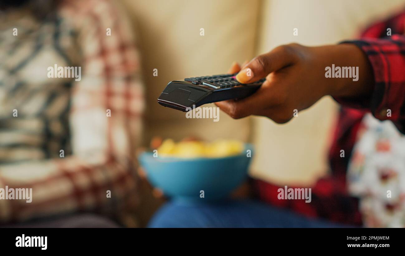 Woman switching channels with tv remote control to watch movie with her ...