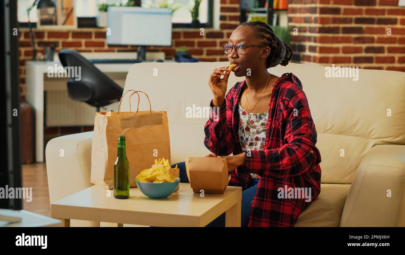 Happy woman eating hamburgers with fries and beer, having fun with ...