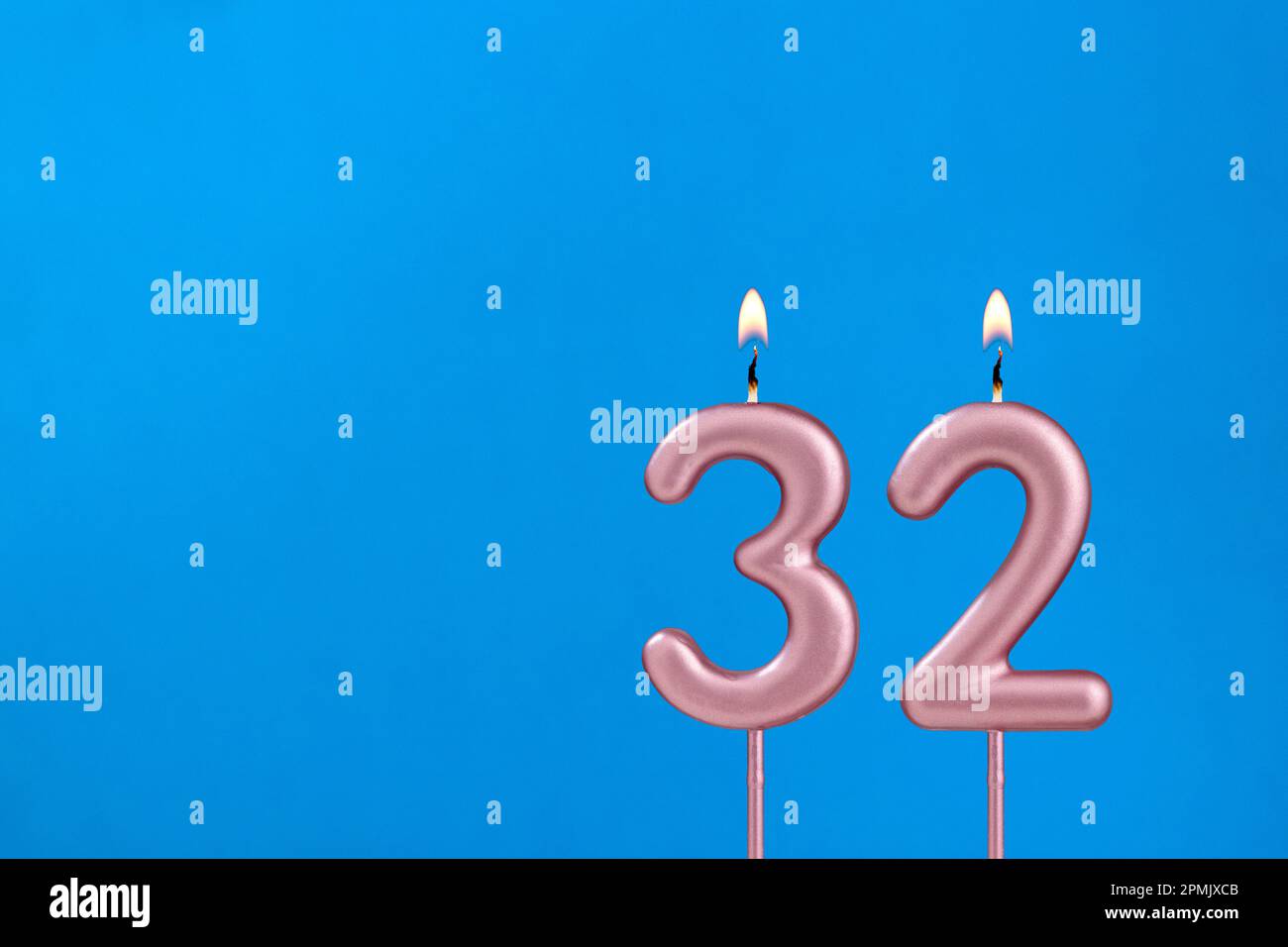 Number 32 - Burning anniversary candle on blue foamy background Stock ...