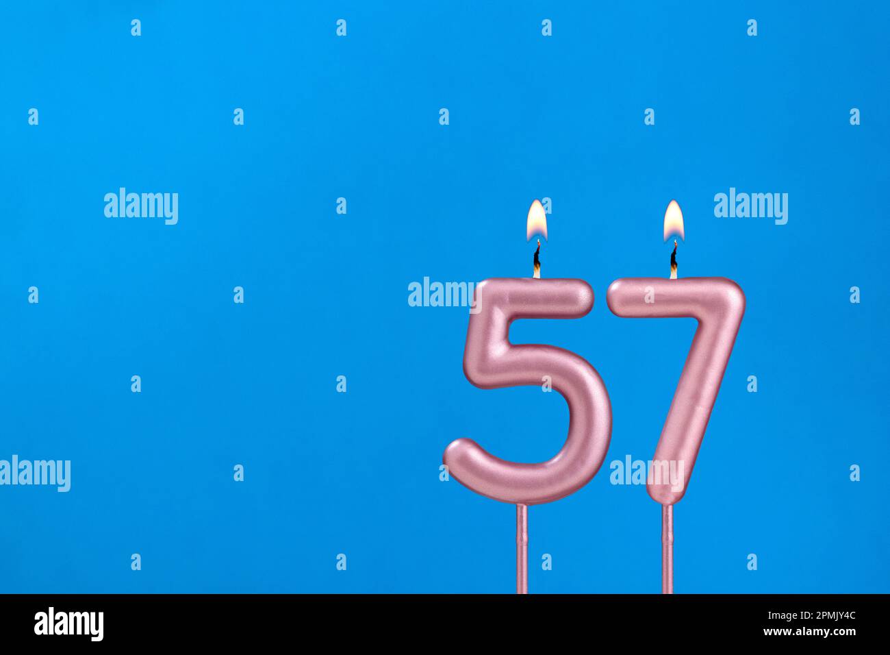 Number 57 - Burning anniversary candle on blue foamy background Stock ...