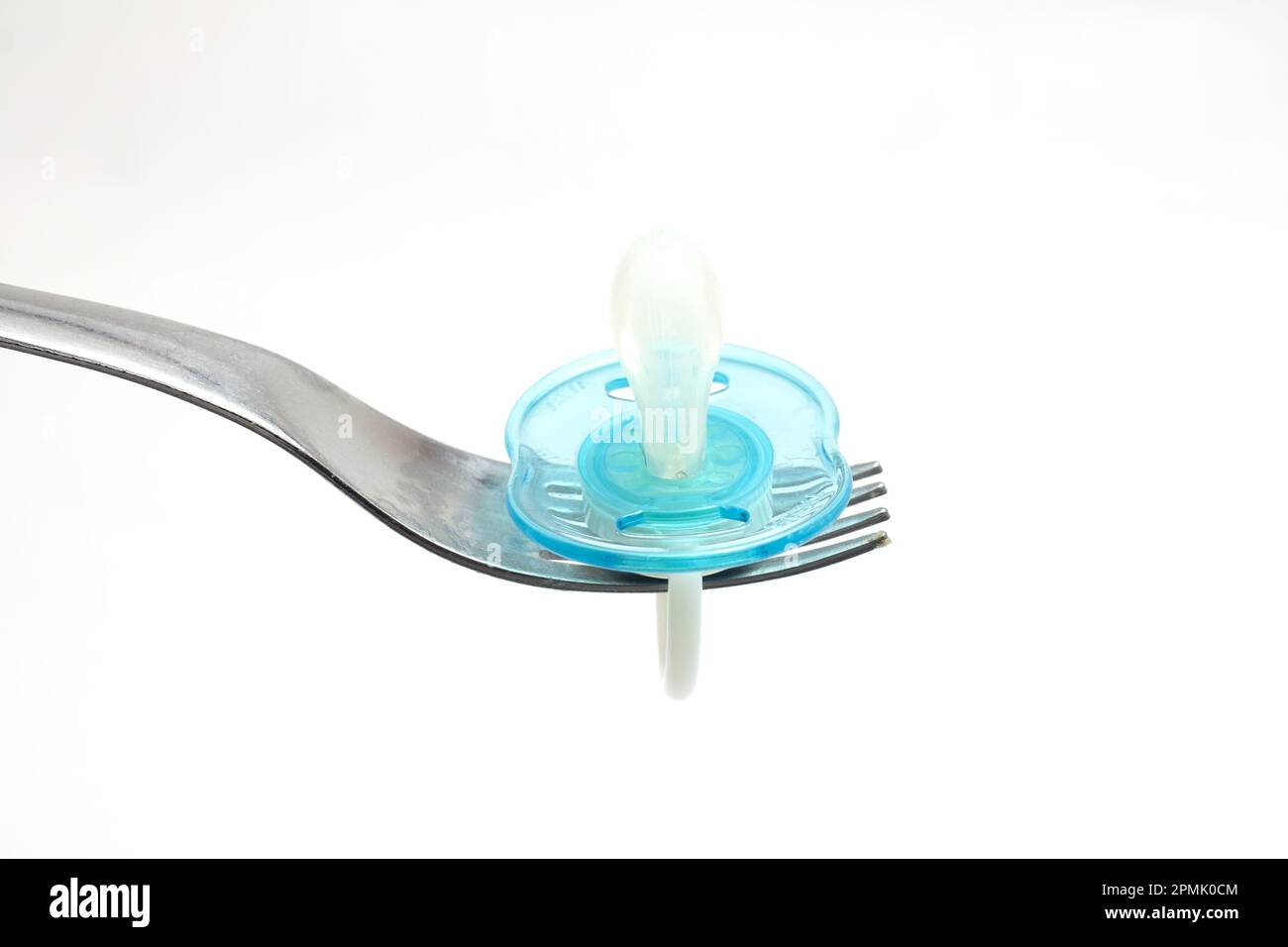 A stainless steel fork with a blue plastic baby pacifier on the tines ...