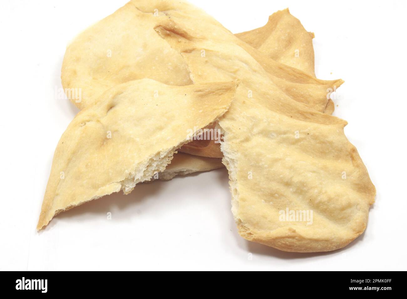 Two pieces of pita bread with a bite taken from one of them, resting on ...