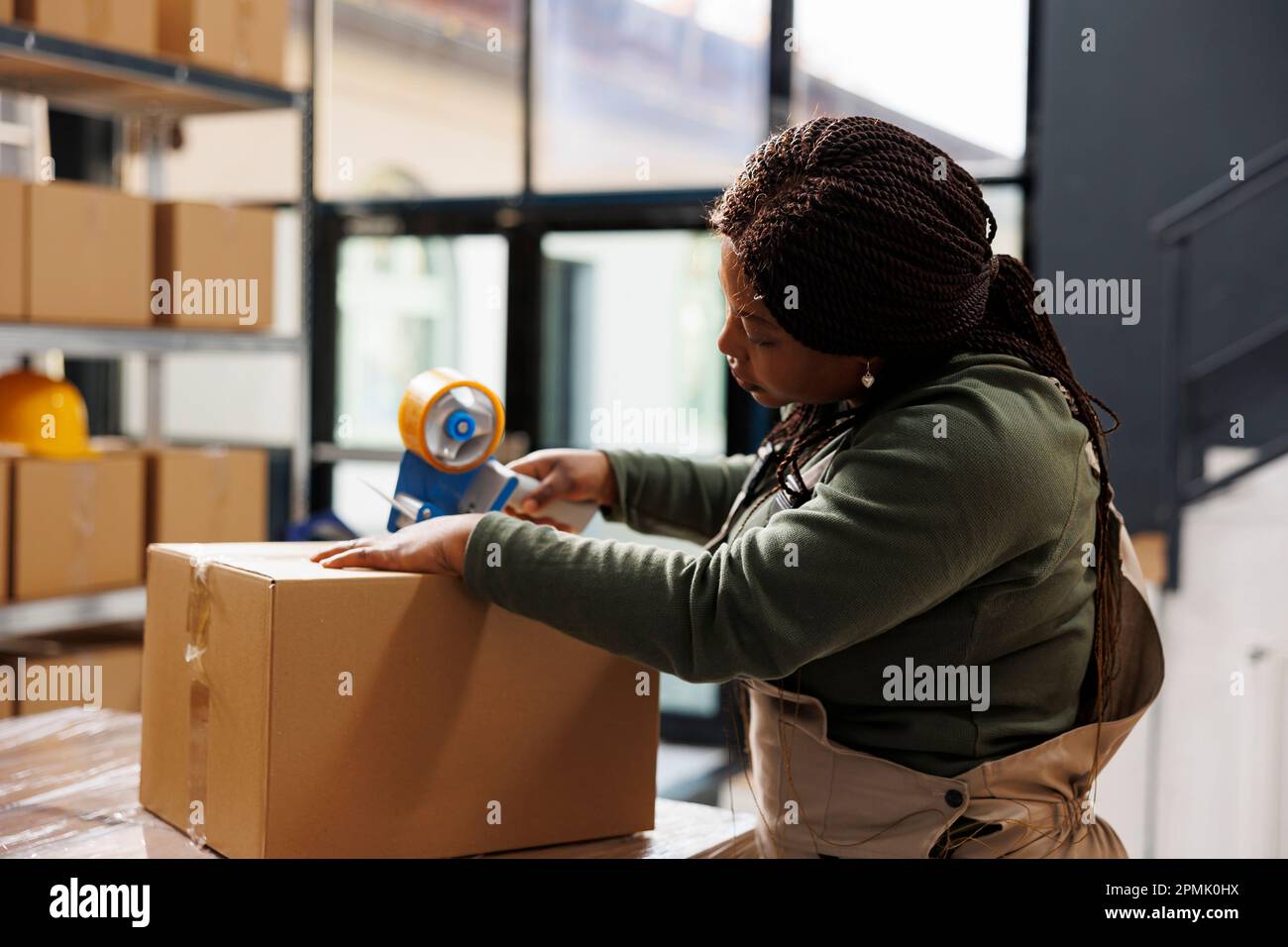 African american worker putting adhesive tape on carton box, preparing ...