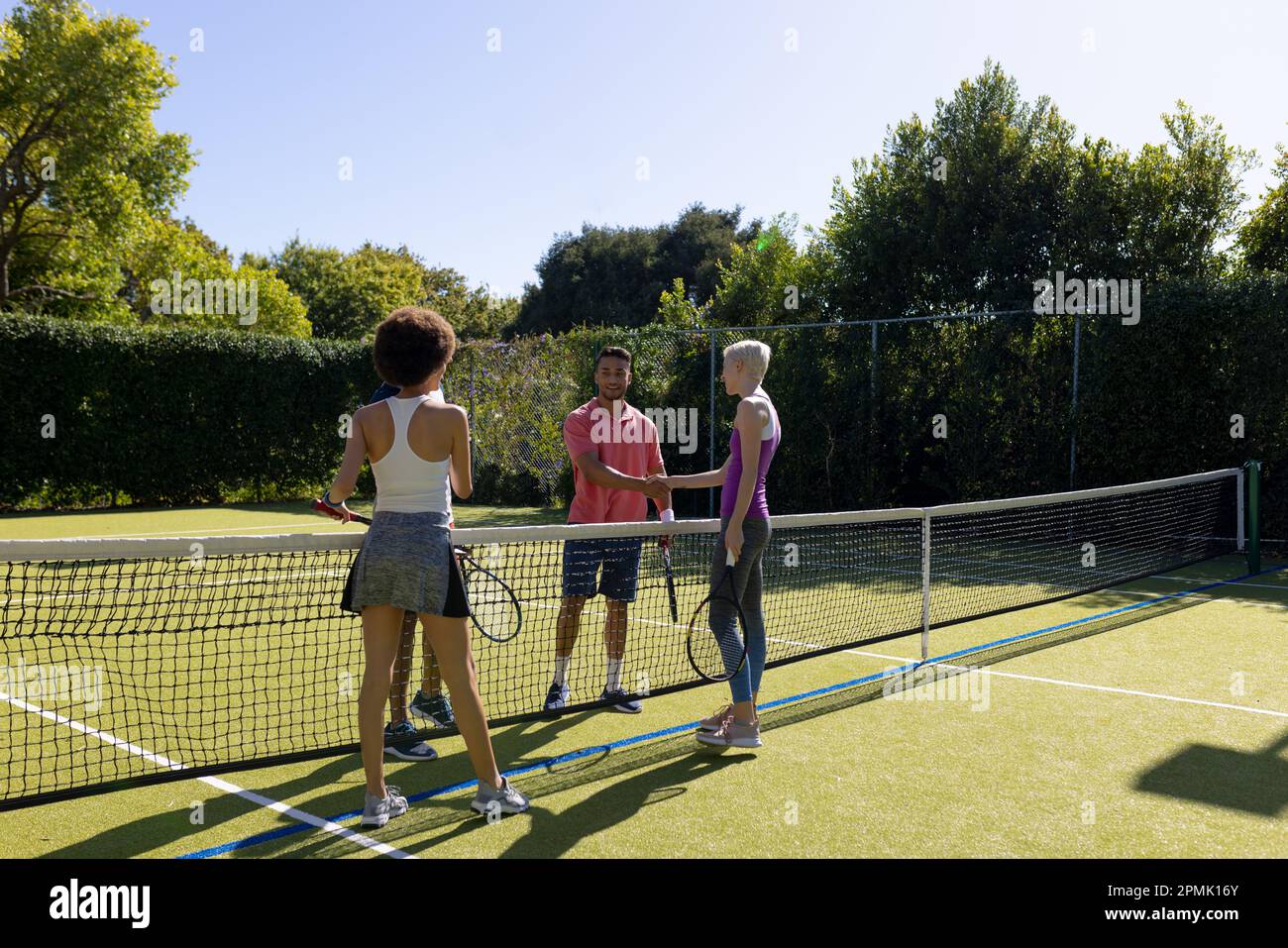 Happy diverse group of friends playing tennis, shaking hands at tennis ...