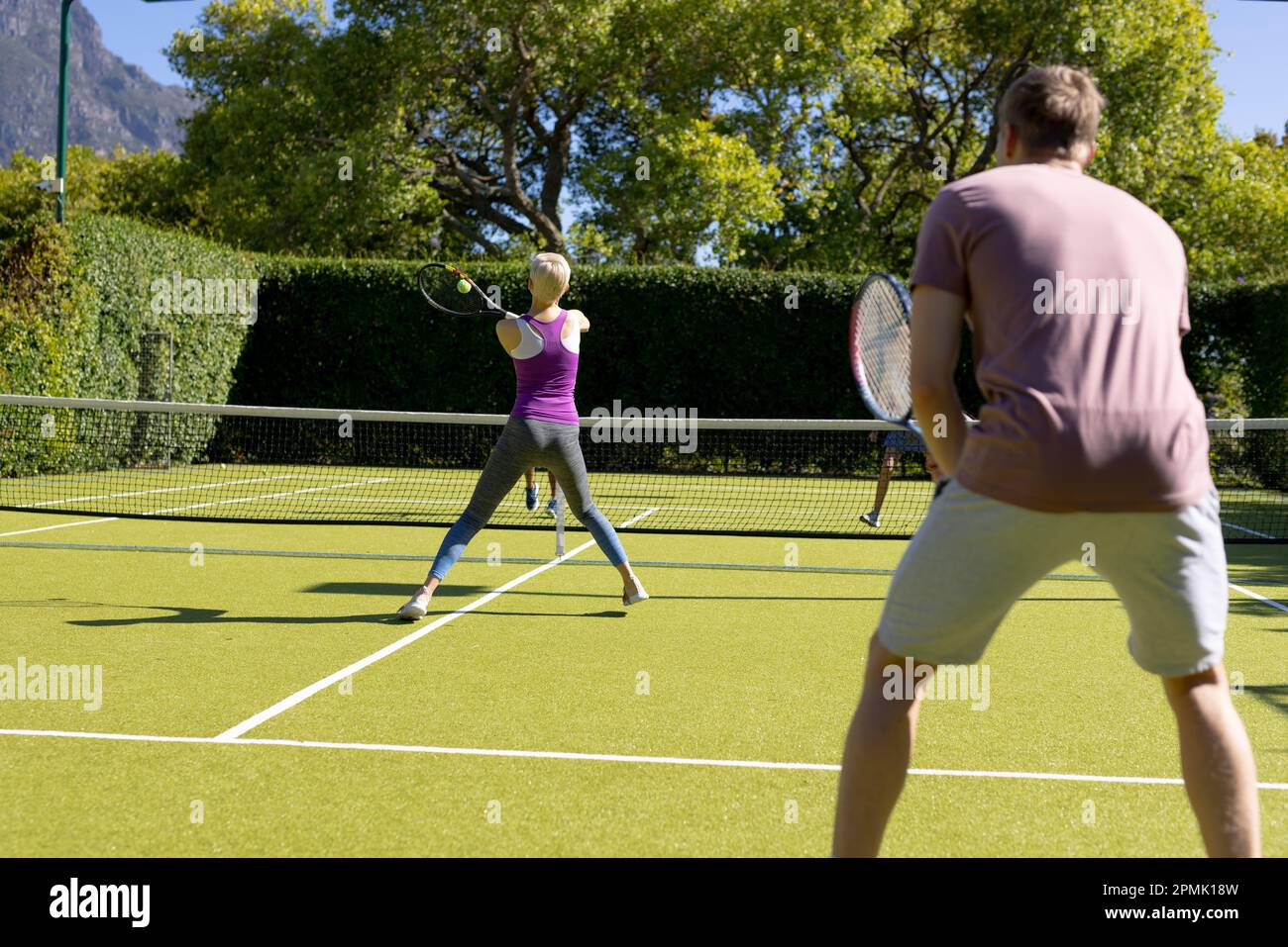 Happy diverse group of friends playing tennis at tennis court Stock ...