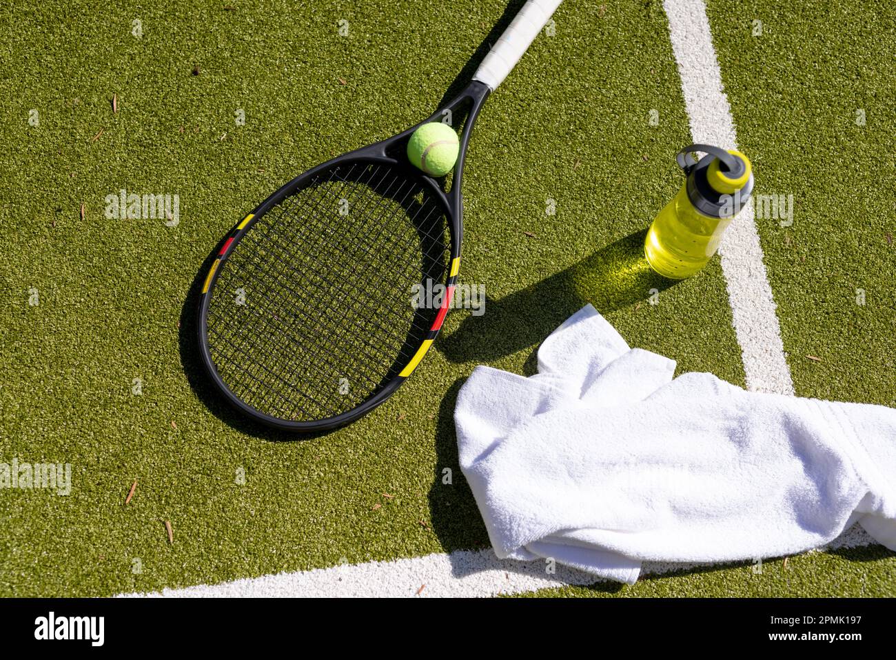 Close up of tennis ball, racket, towel and water bottle at tennis court ...