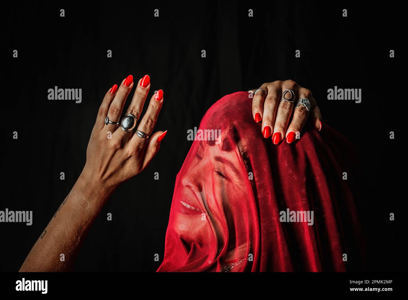 Beautiful woman with red cloth over her head making hand gestures ...