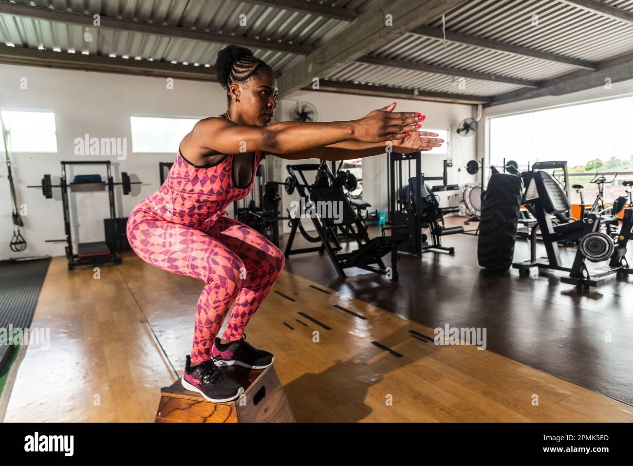 Determined woman doing squat exercises with arms out in front. Body ...