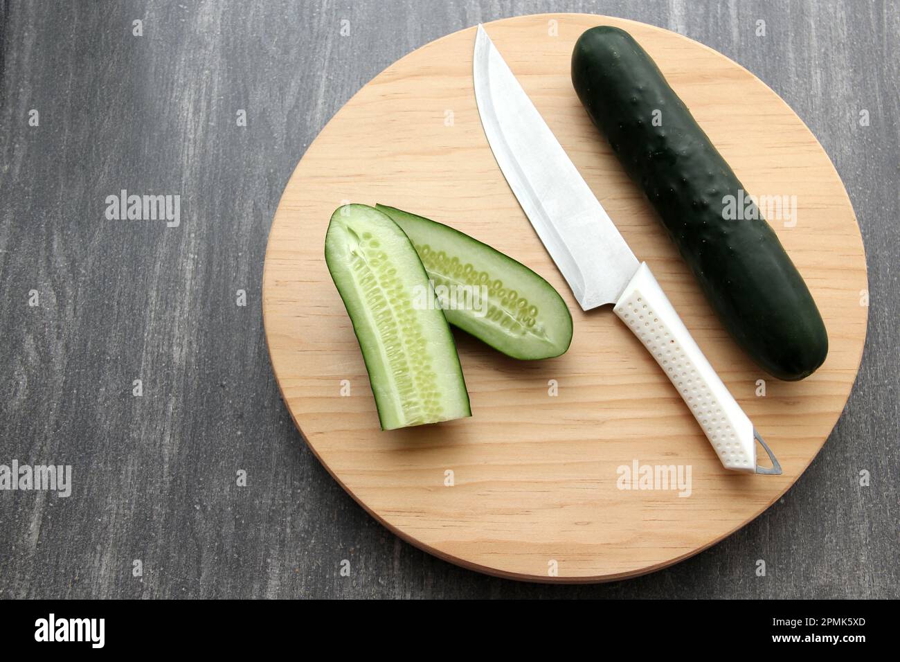 Fresh, green cucumbers on a chopping board with knife are prepared for ...