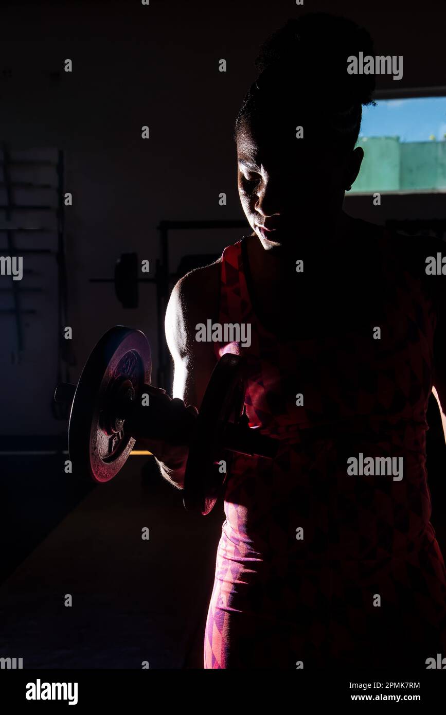 Dramatic portrait of fitness woman doing exercise for arm muscle. Gym ...