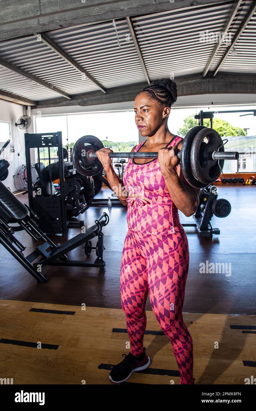 Determined woman lifting weights at the gym. Strengthening the arms ...