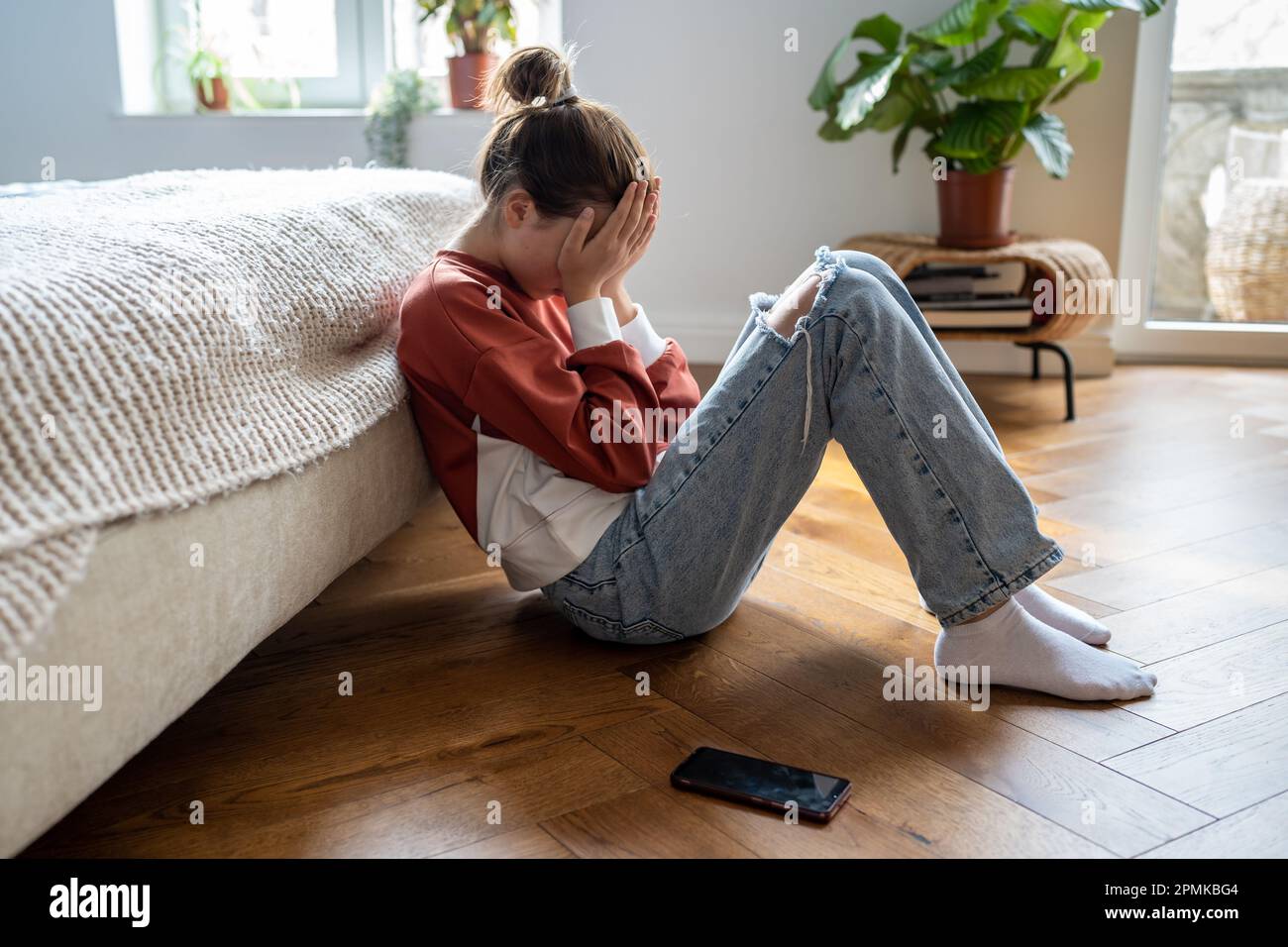 Unhappy teen girl covering face with hands crying while sitting on ...