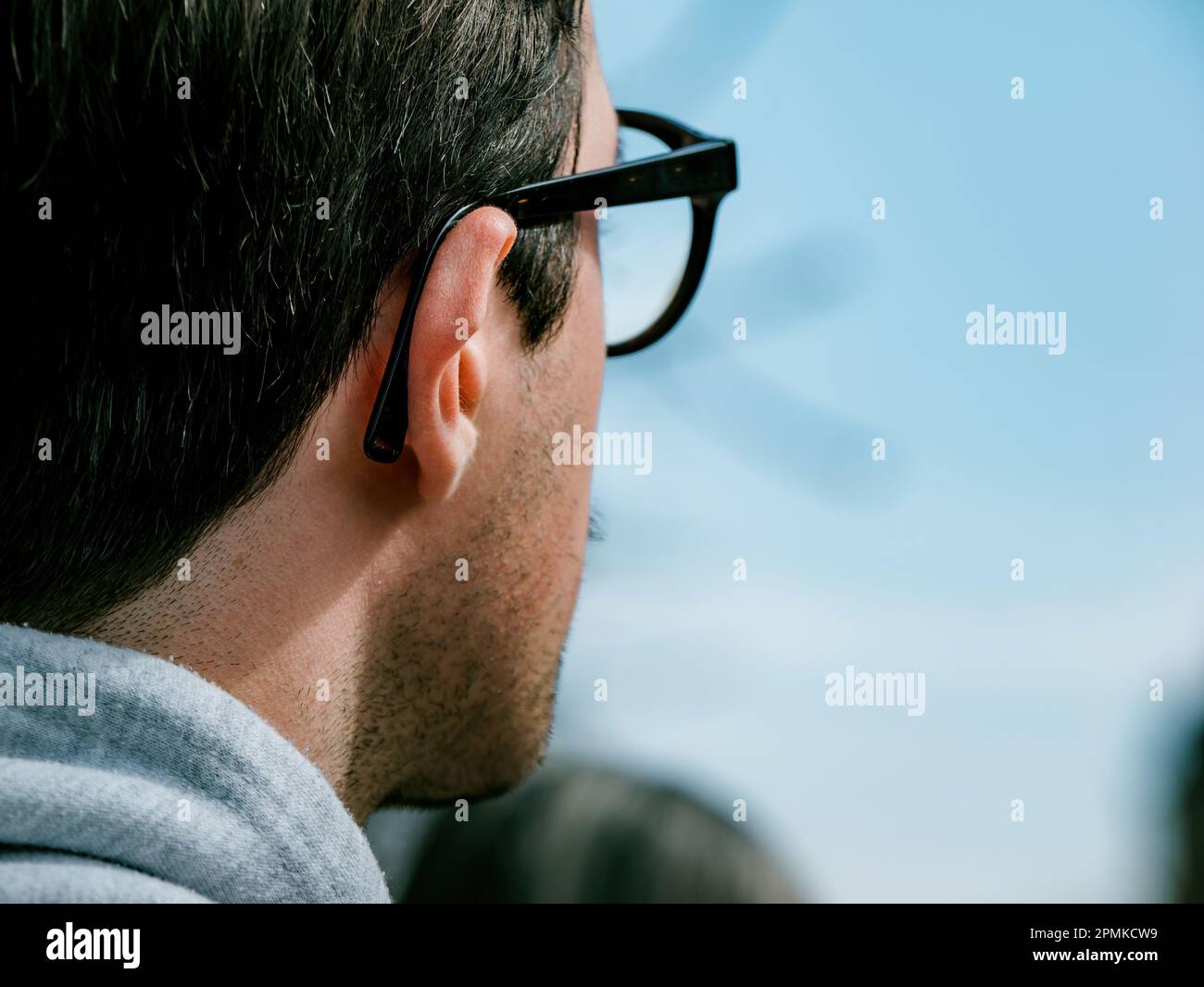 An adult male with glasses and facial hair in a close-up rear view ...