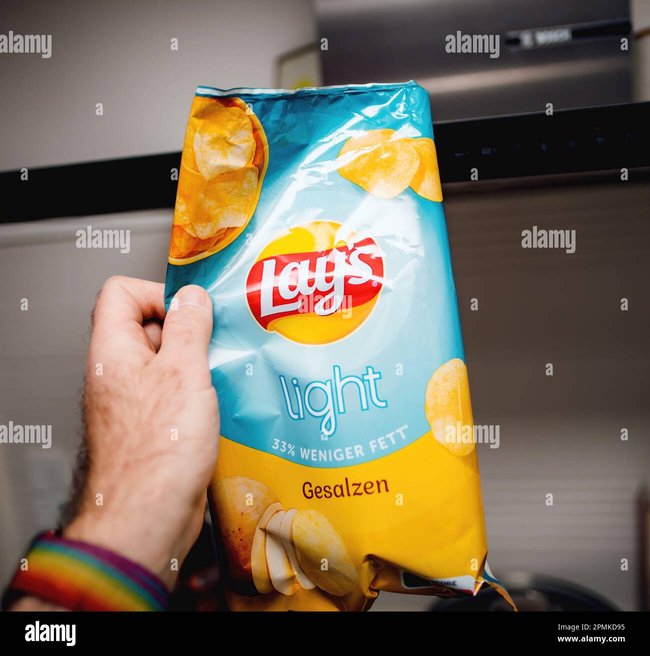 Frankfurt, Germany - Mar 6, 2023: A person holds a yellow packet of Lays Light chips; the ...