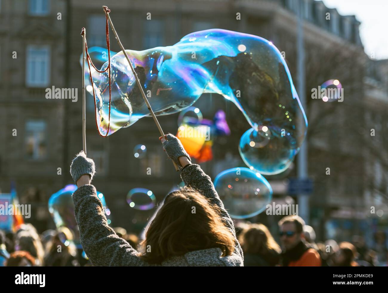 A group of people are creating huge, bright soap bubbles in mid-air ...