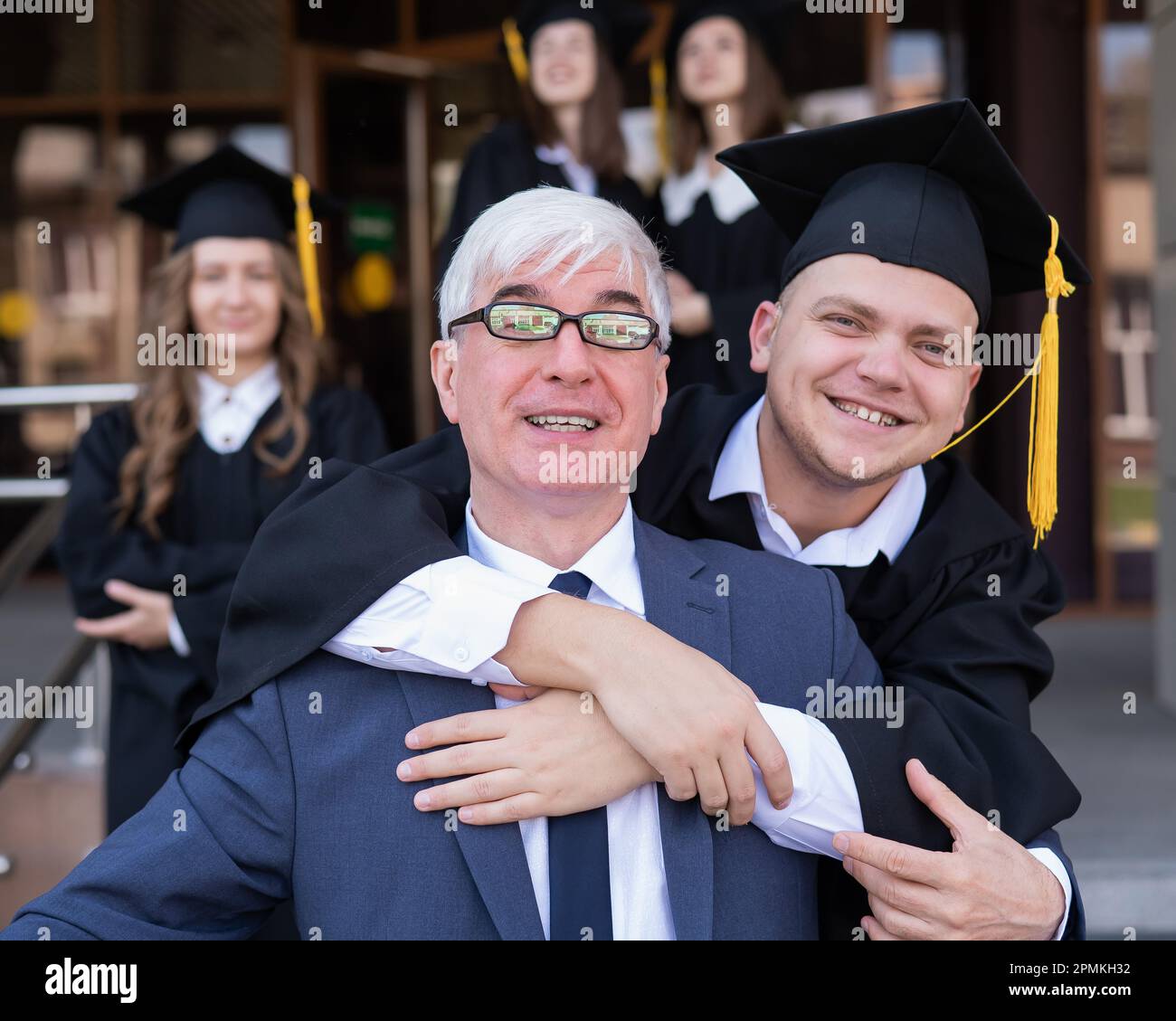 Father and son embrace at graduation. Parent congratulates university ...