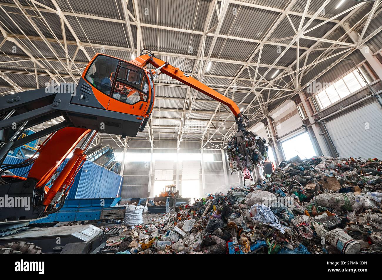 Excavator grabs trash in warehouse of waste processing plant Stock ...