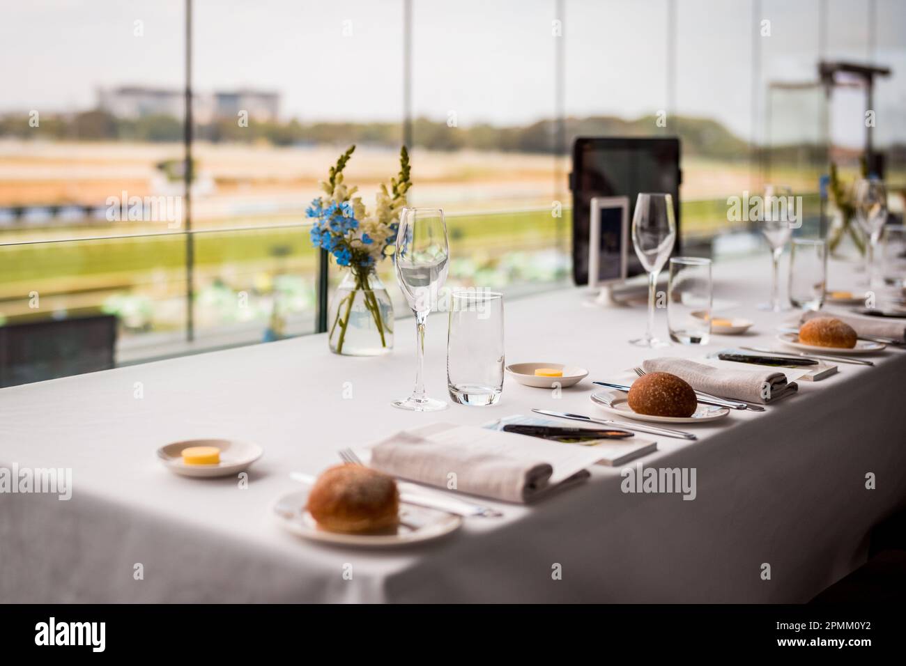 Table with glasses, cutlery and food with the horse racing track in the ...