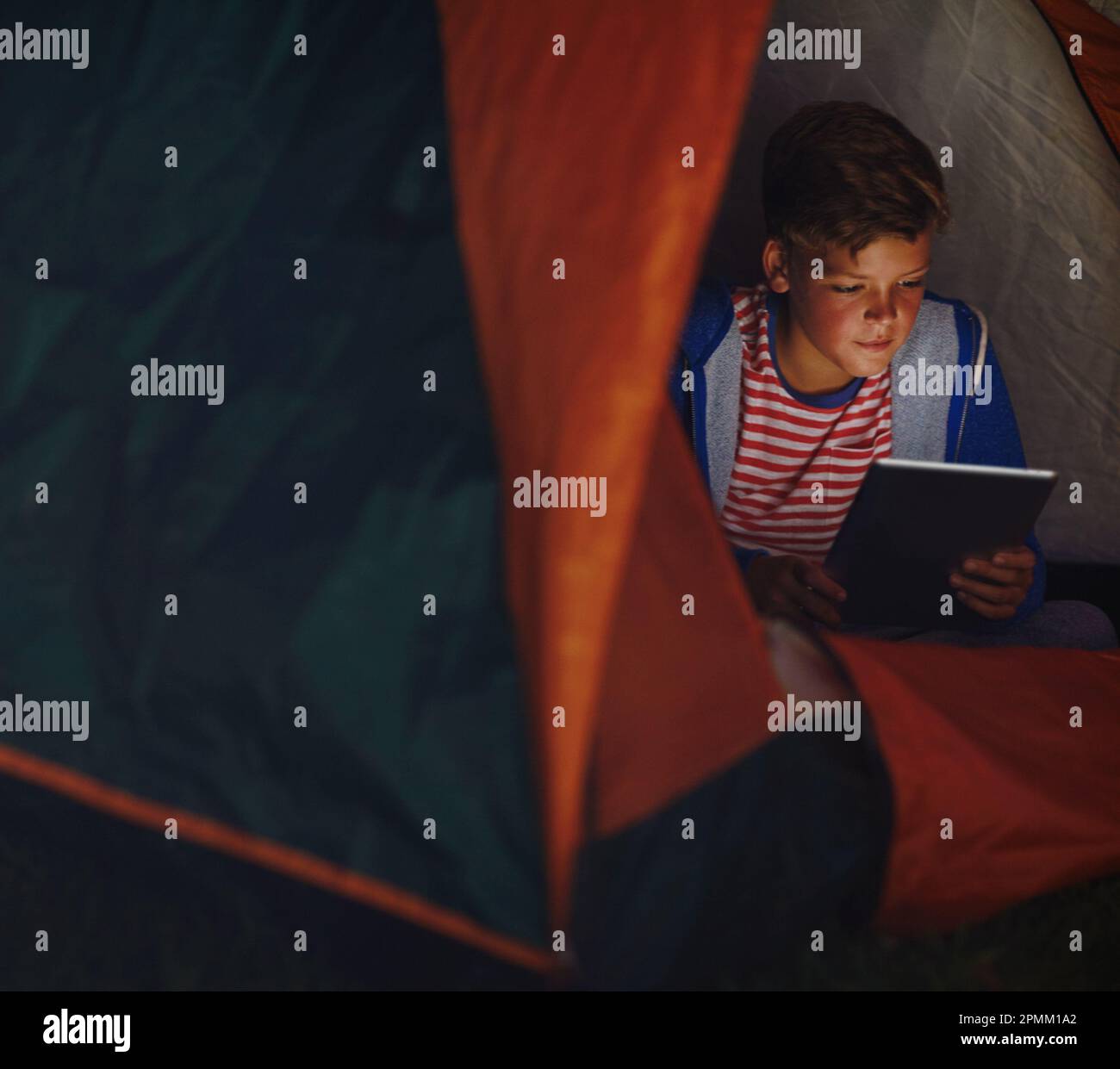 Connected while out camping. a young boy using a digital tablet while ...