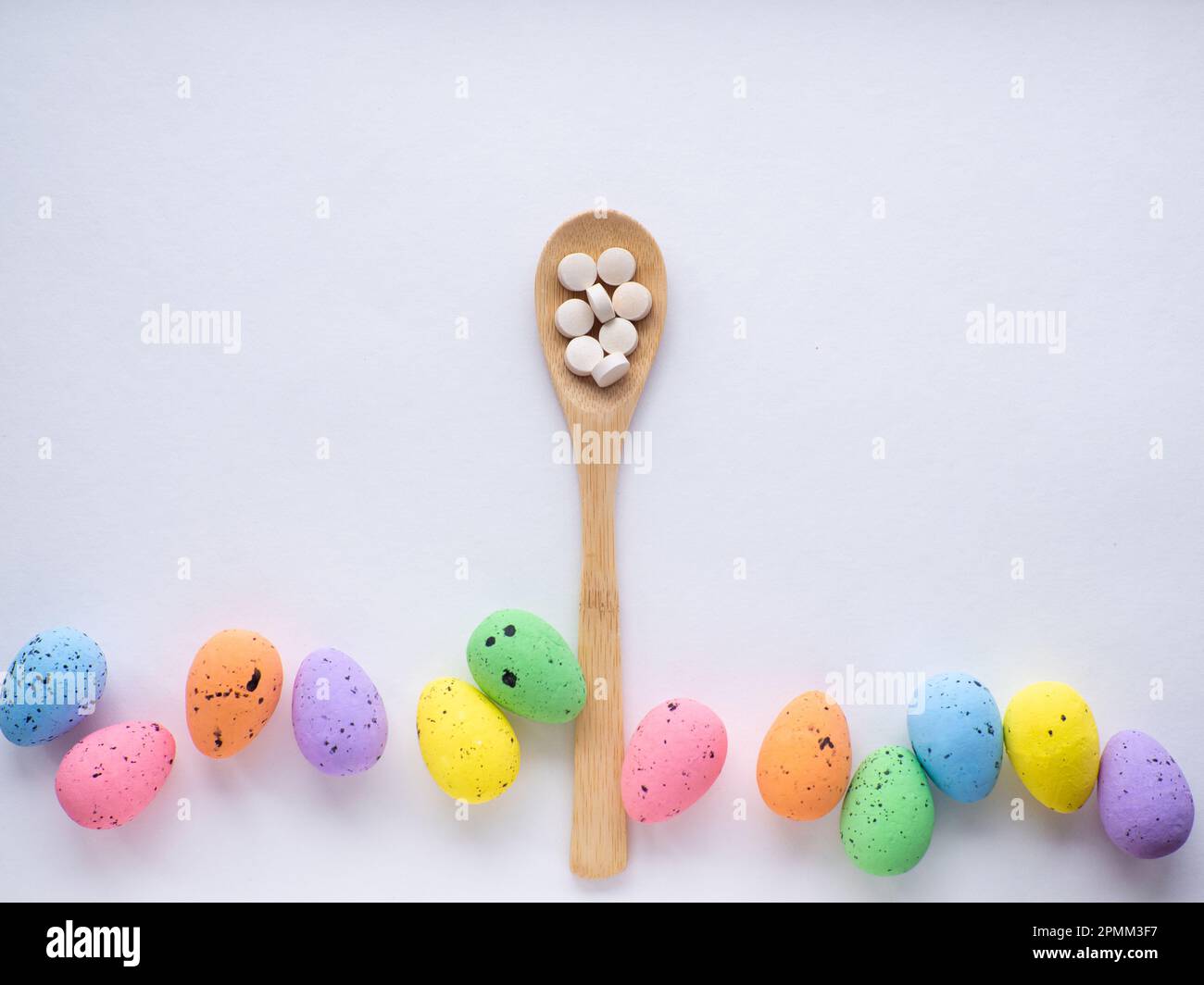 Easter and medicine. Healthy Easter concept. Pills in wooden spoon ...