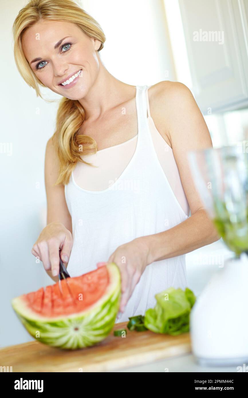 Slicing into a juicy watermelon. Attractive blonde woman slicing a ...