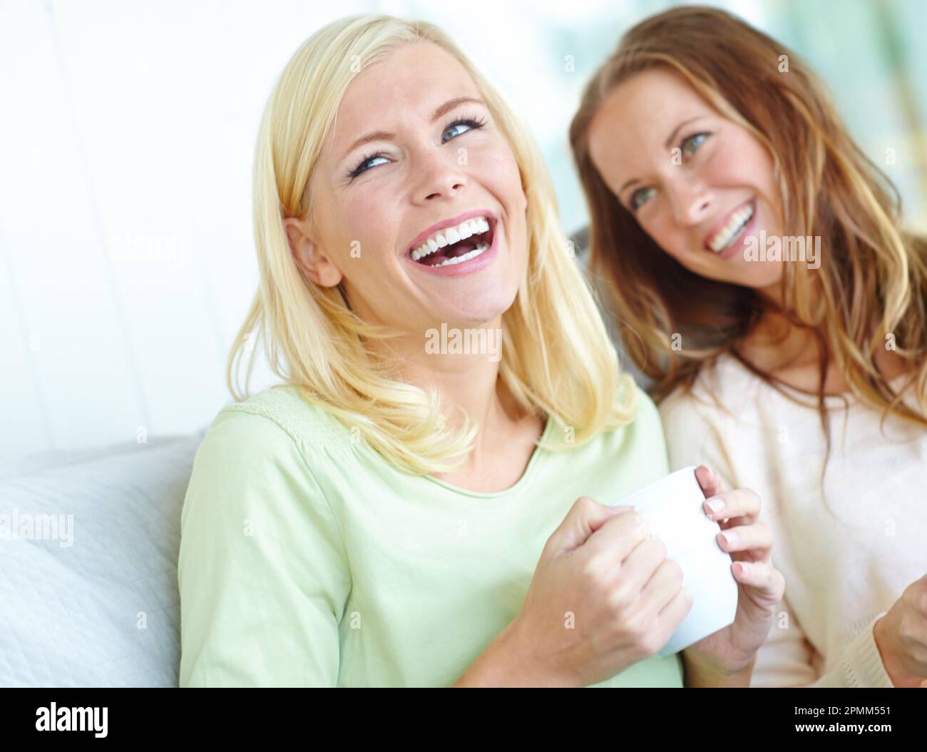 Catching up over coffee. Two attractive young women smiling while ...