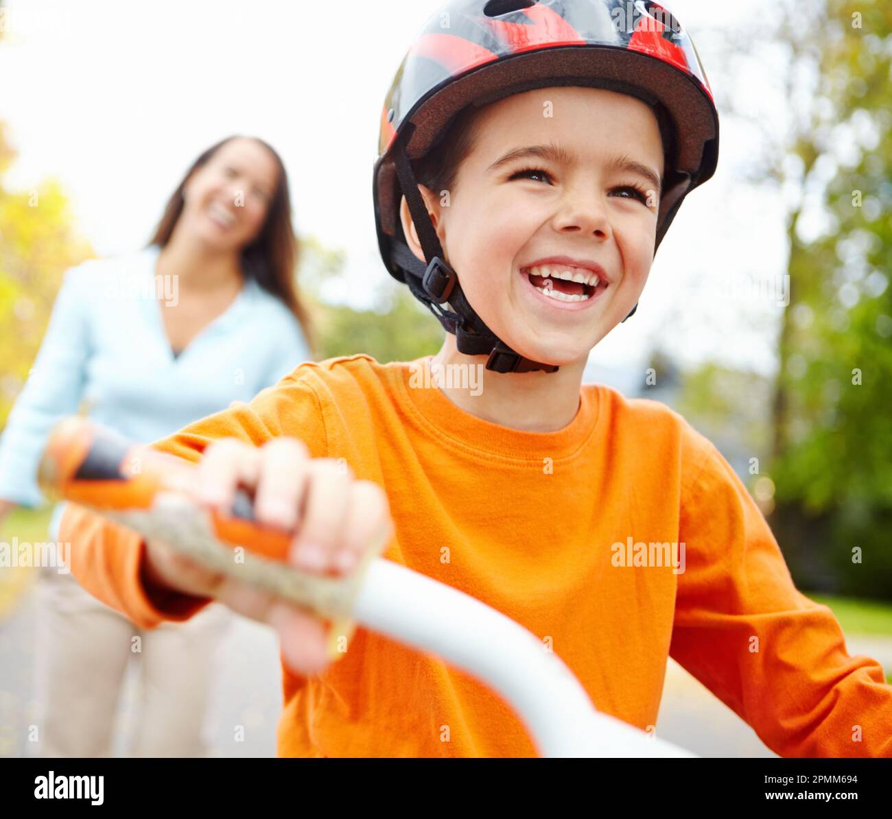 Young and carefree. A little boy riding a bicycle in the park with his ...