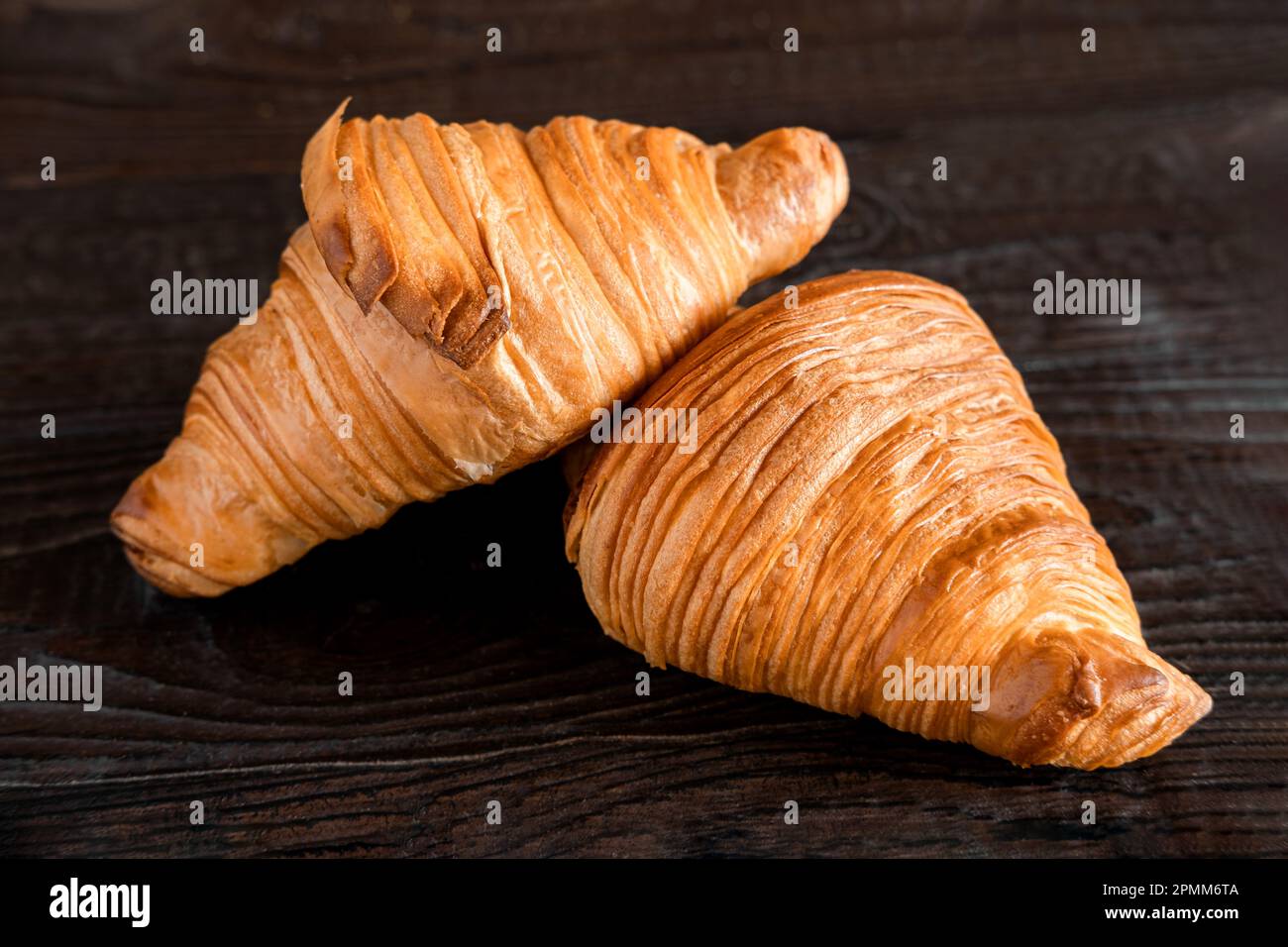 Two croissants on a wooden cutting board. Rustic dark table. Food ...