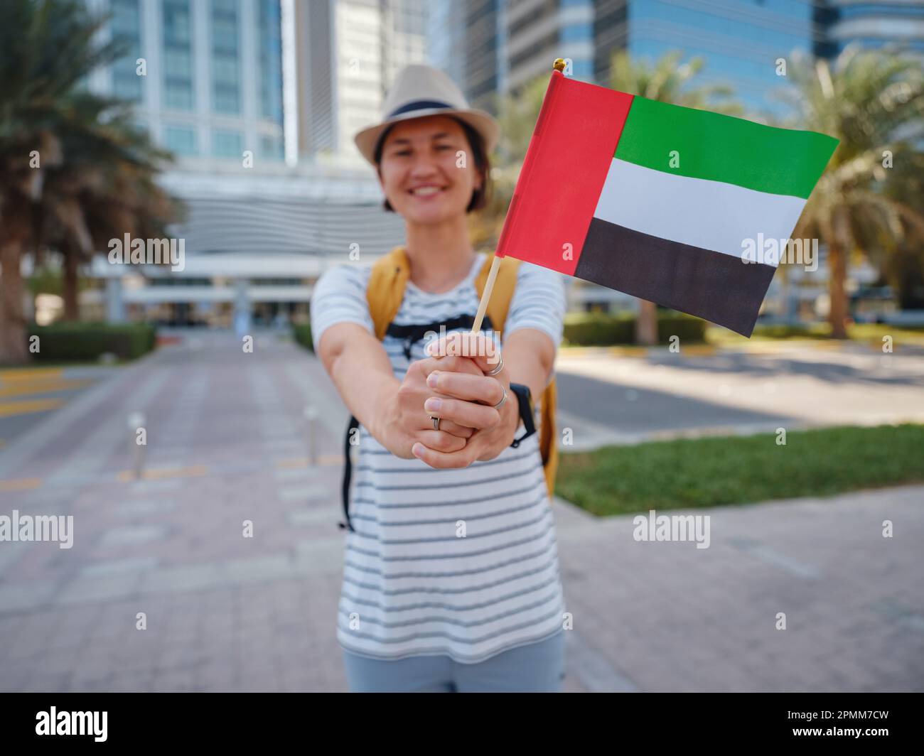 Happy young asian female traveler with backpack and hat with UAE flag ...