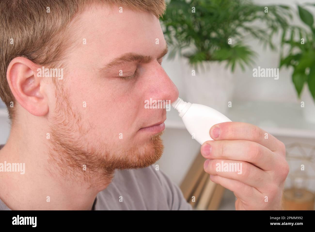 An adult male uses a nasal spray to relieve a runny nose. The concept ...