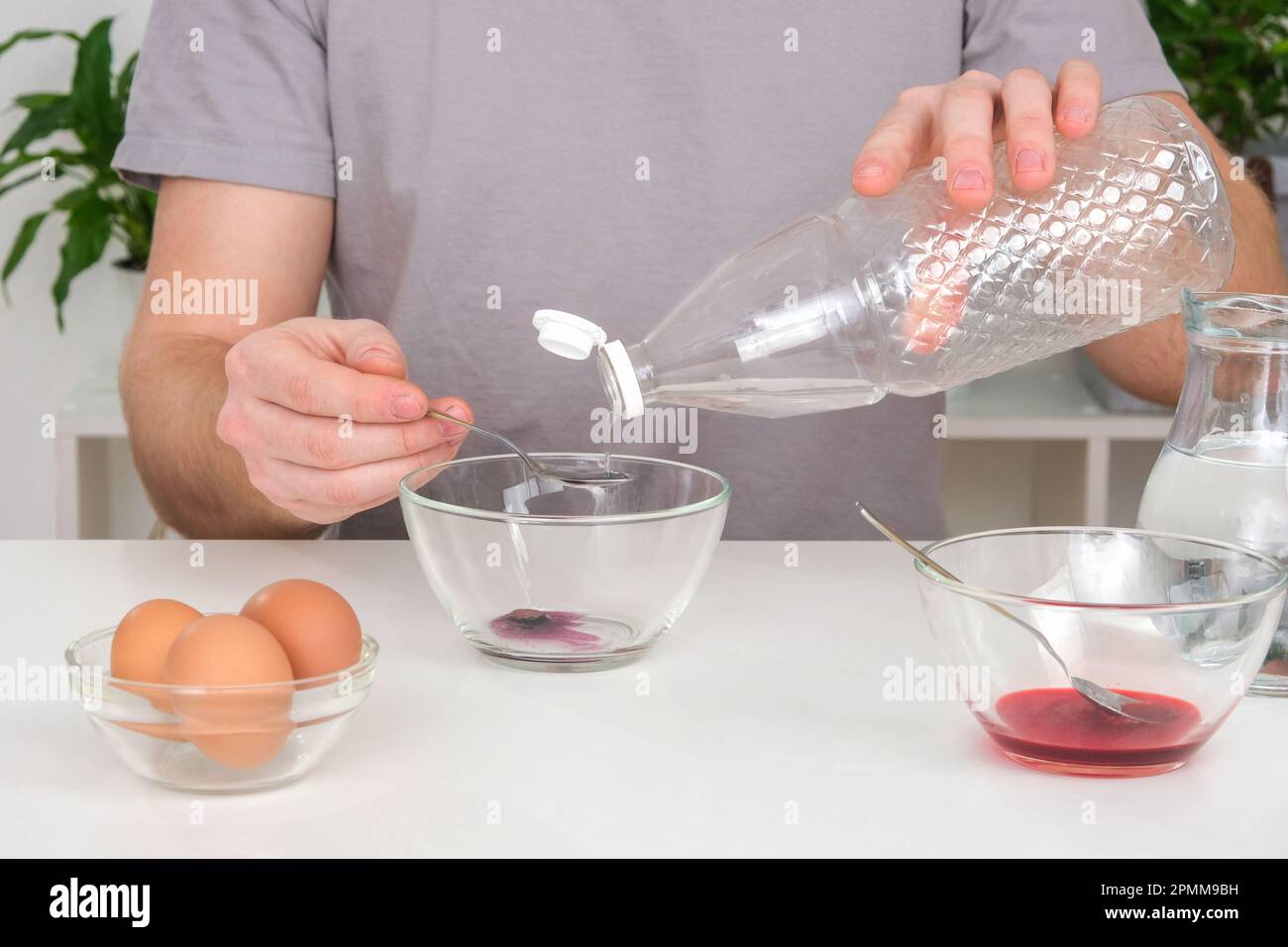 A man pours a spoonful of vinegar into a glass cup with dye. Dyeing ...