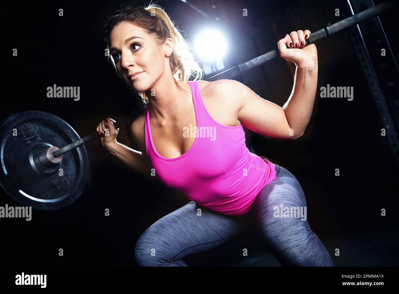 Building the perfect body. A well-toned young woman lifting a heavy ...
