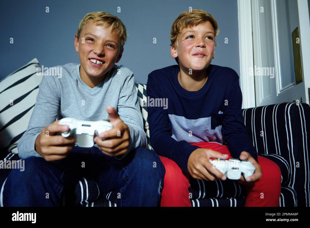 Its all fun and games. young boys playing video games Stock Photo - Alamy