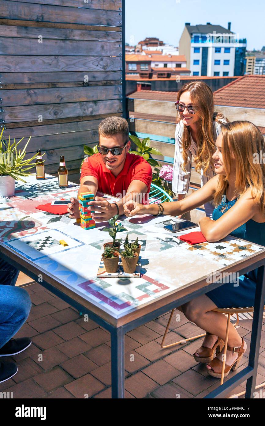 Group of friends playing with jenga game in rooftop on a summer party ...