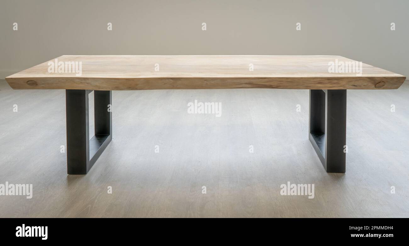 A modern table with a thick wooden top and metal legs, top made of ...