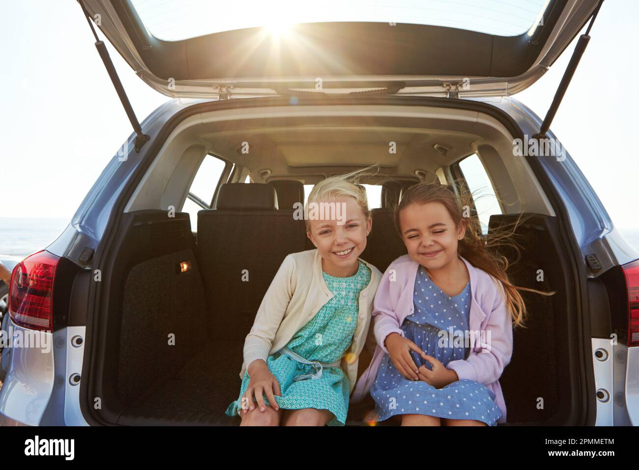 Ready for a road trip. two little girls sitting in the trunk of a car ...