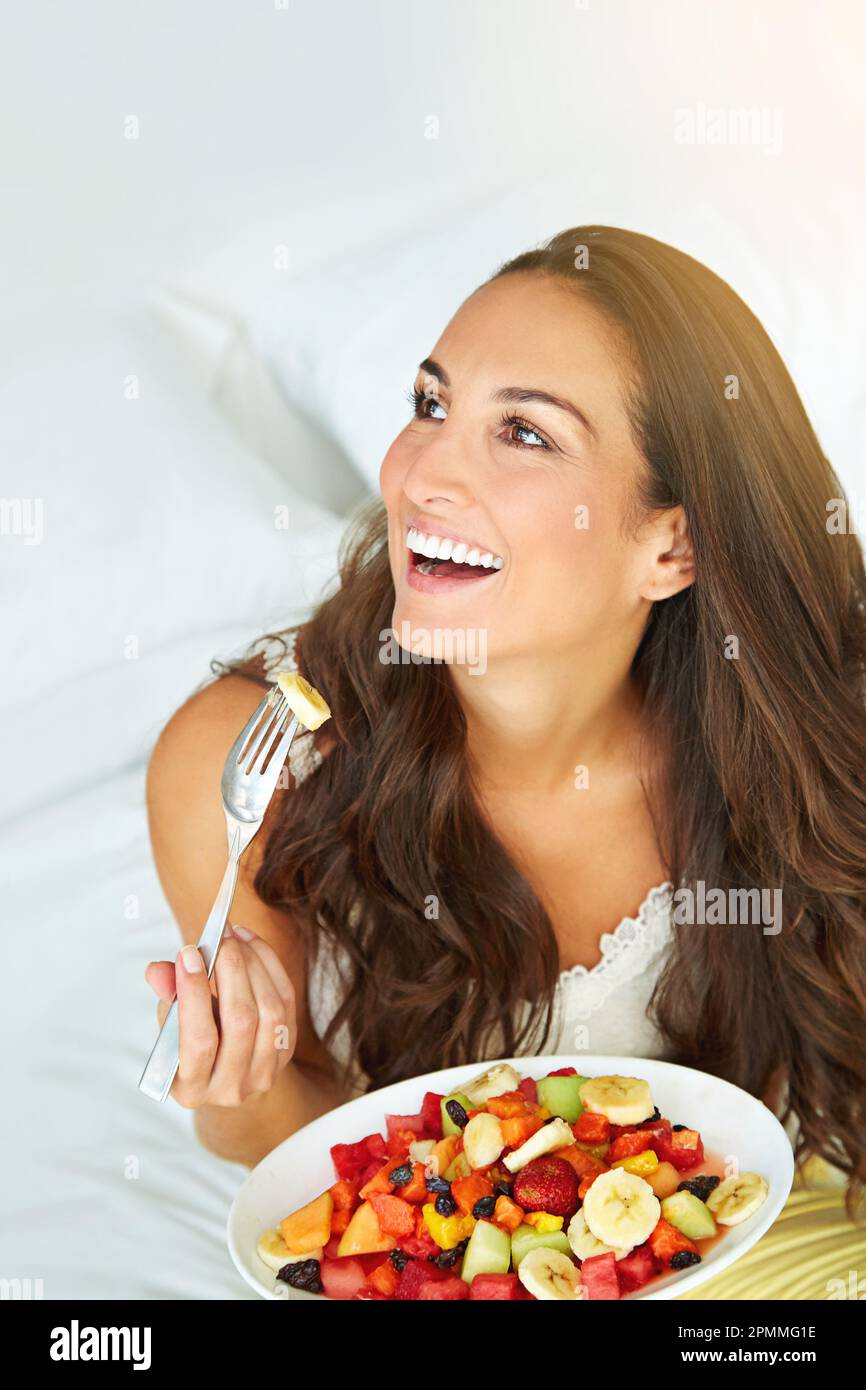 Healthy choices can taste amazing. a young woman eating a fruit salad ...