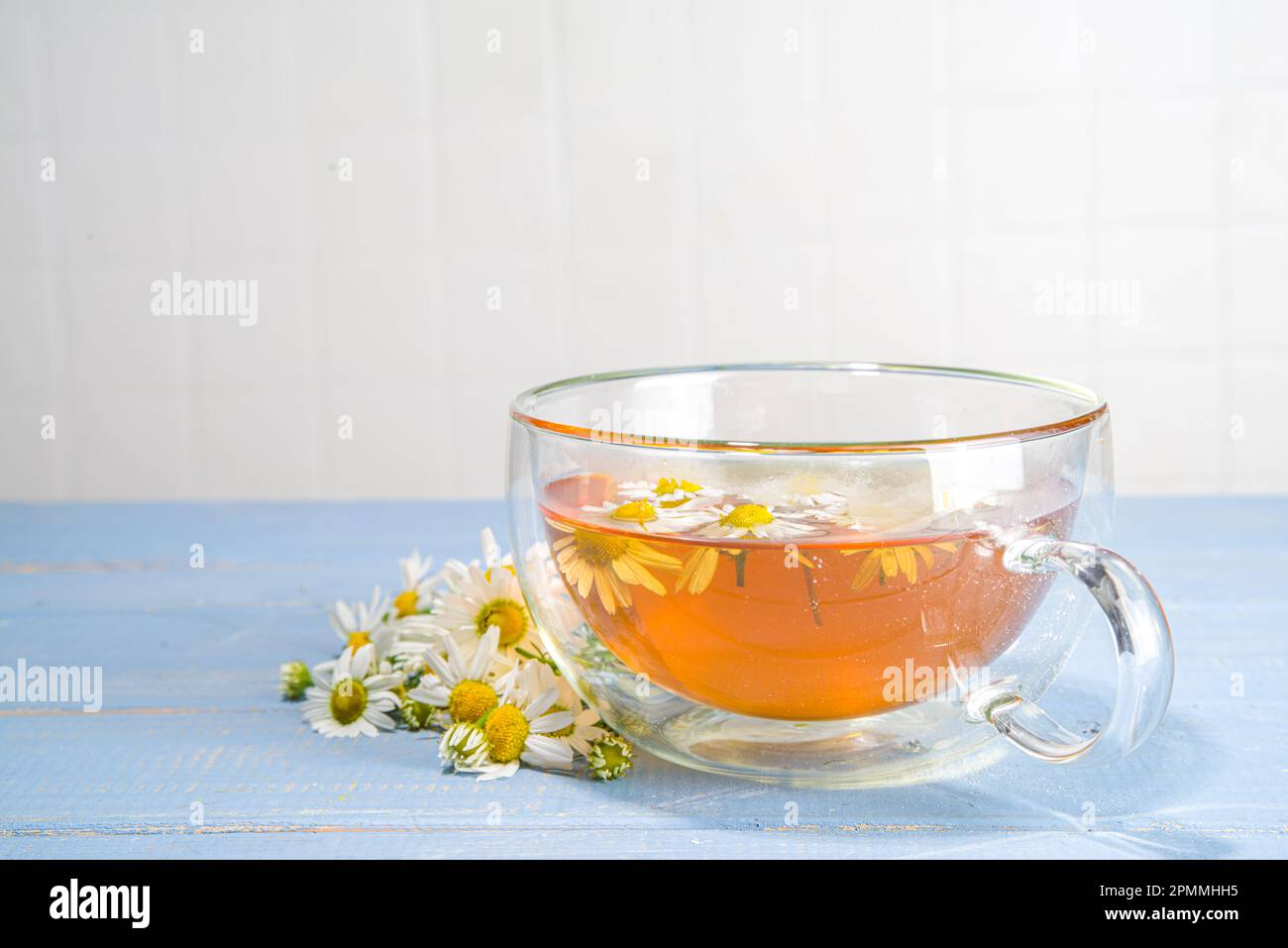 Cup of brewed chamomile tea with bouquet of chamomile daisy, blue ...