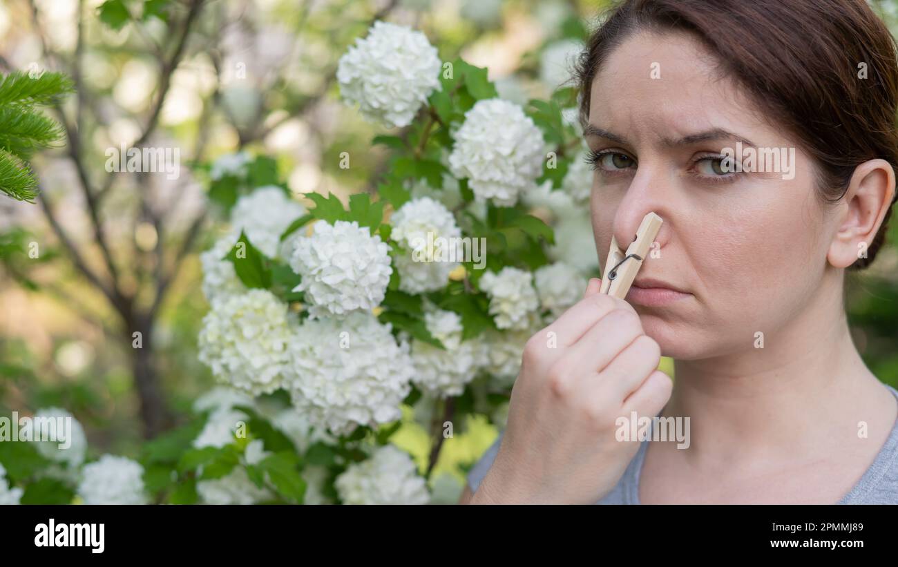 Unhappy woman with a clothespin on her nose on a walk in a blooming ...