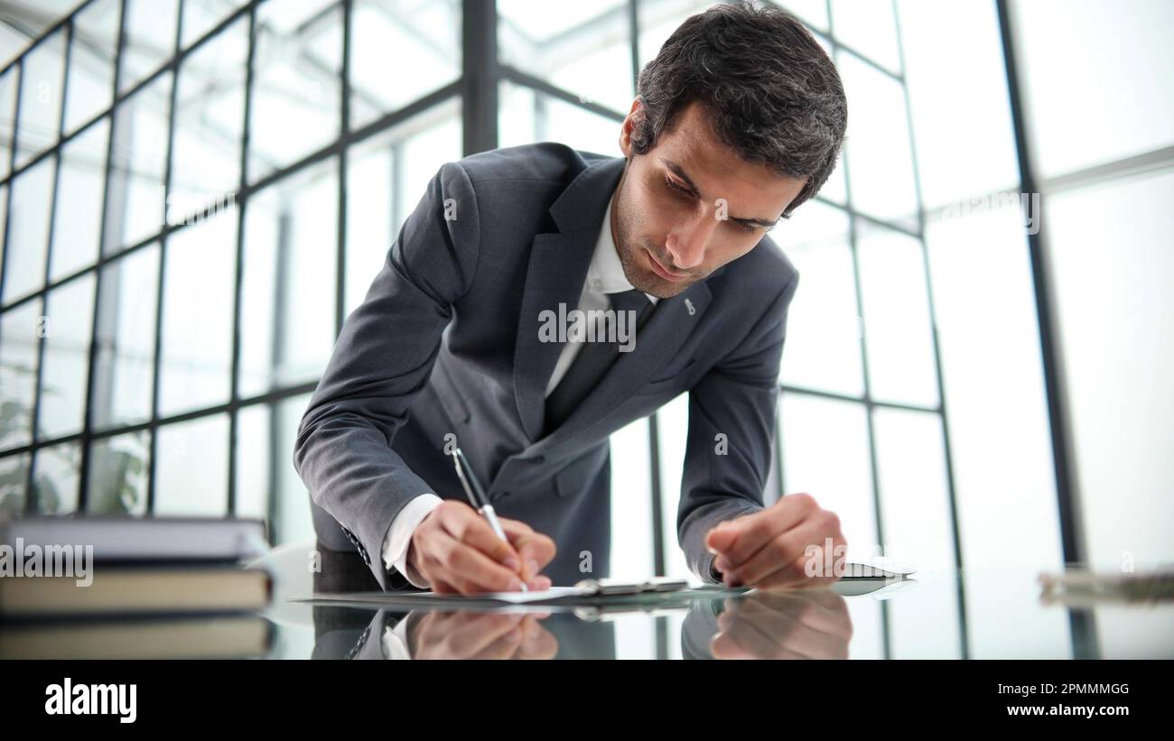 A shot of a person signing documents leaning over a table Stock Photo ...