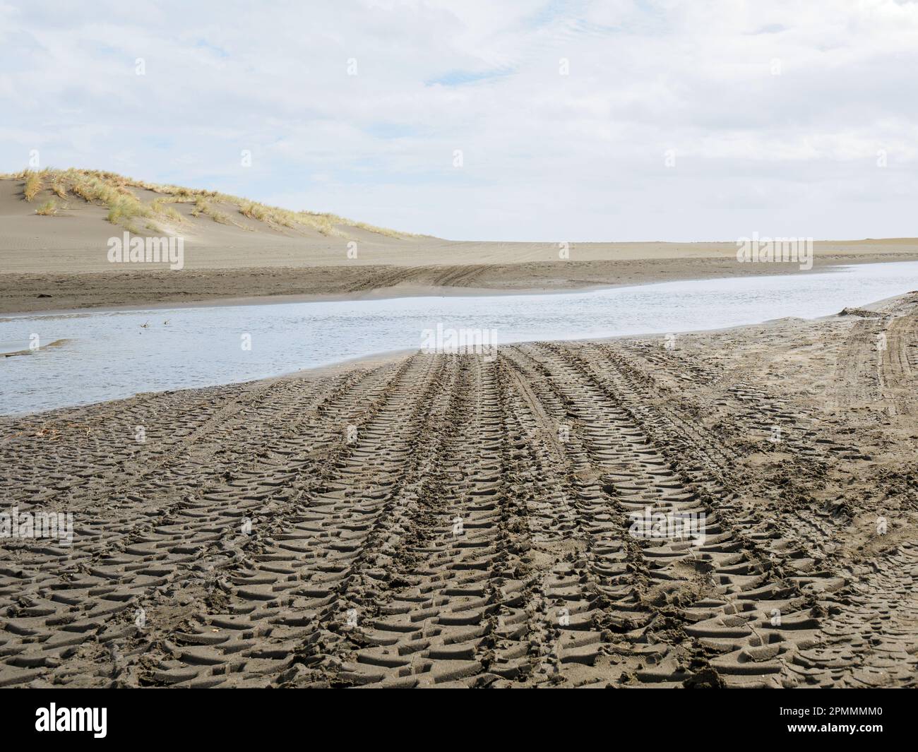 A sandy road with a set of tire tracks leading through it Stock Photo ...