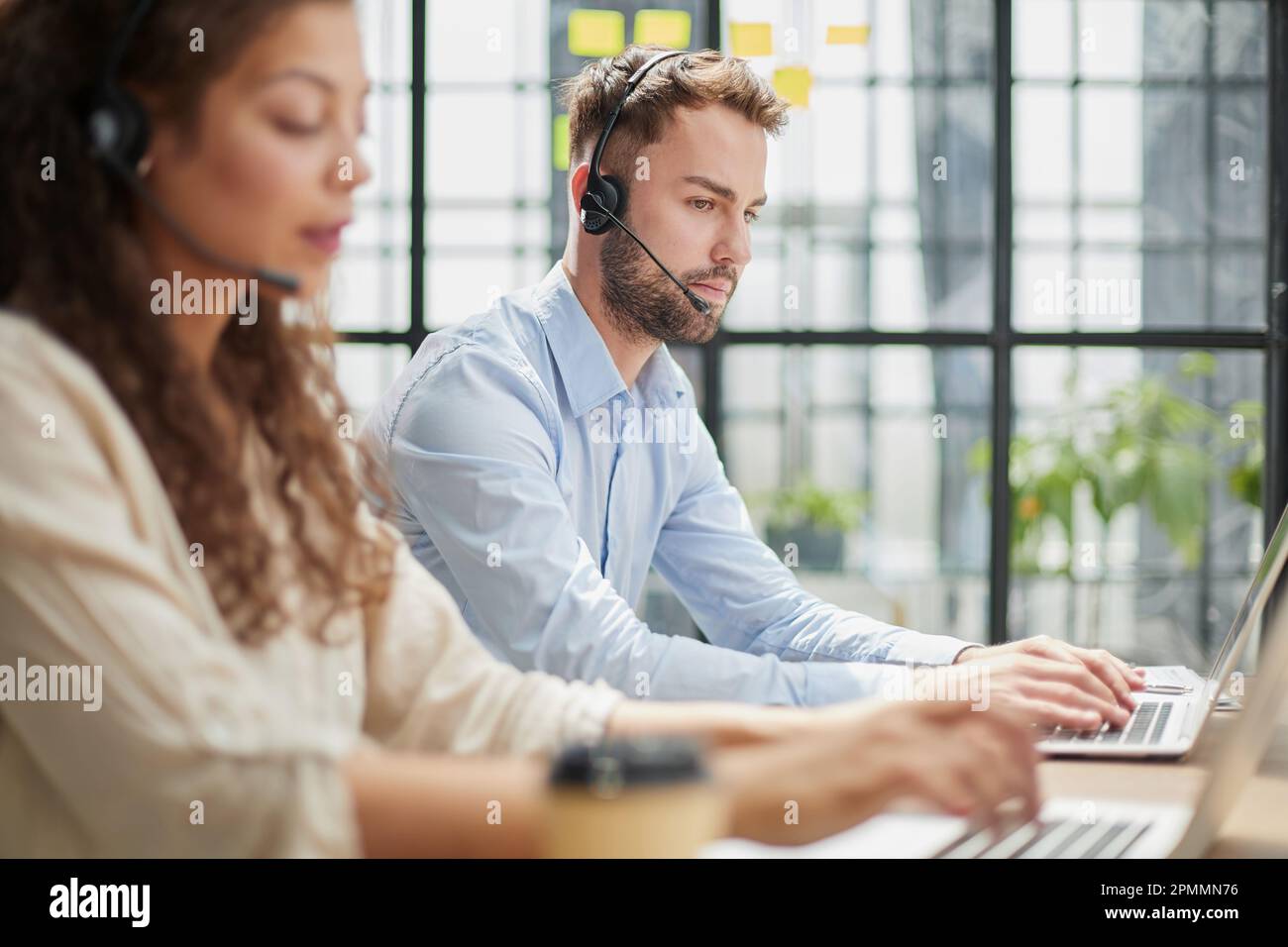 male call-center operator with headphones sitting at modern office ...