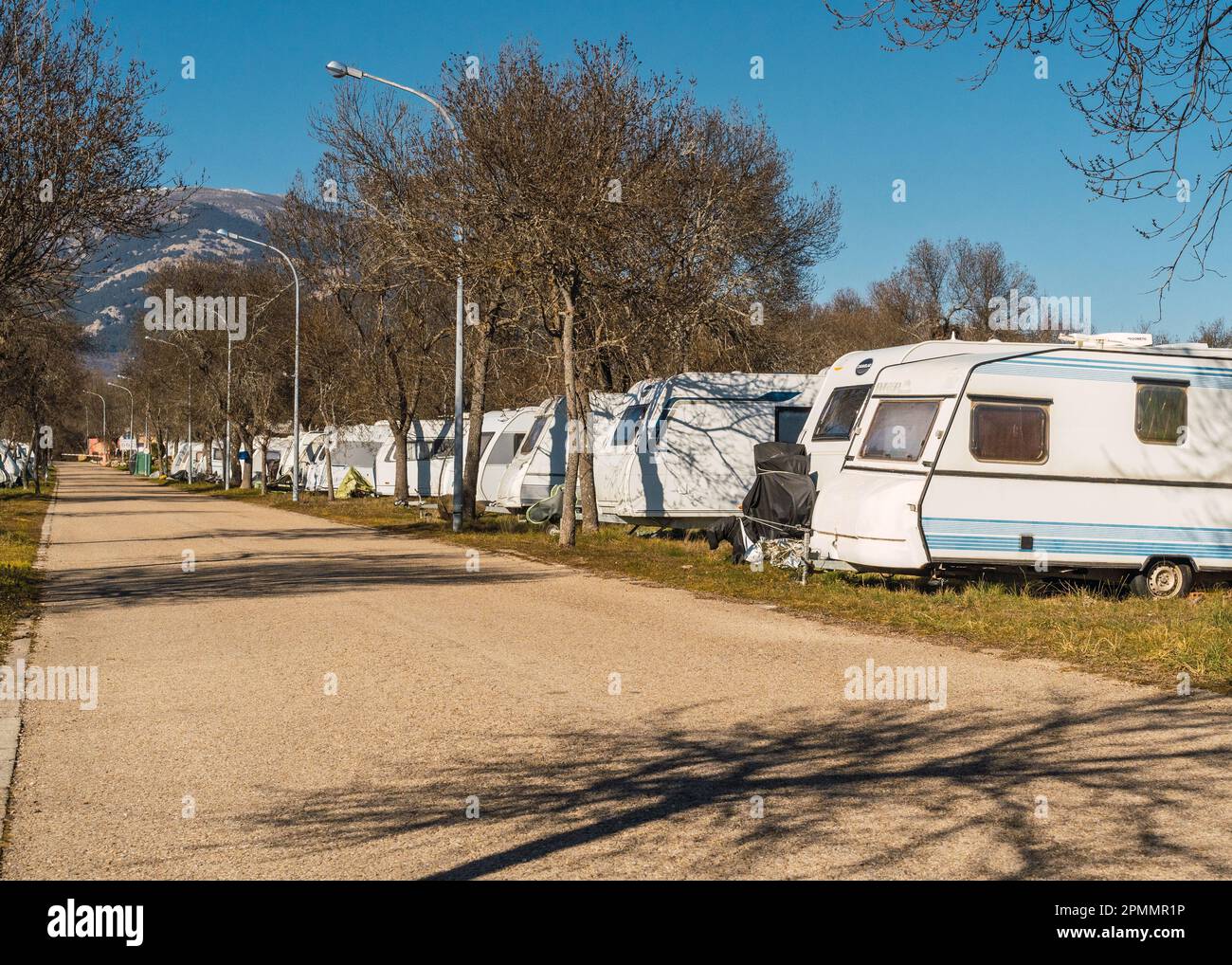 A row of vehicles parked in a line along a roadside with trees Stock ...