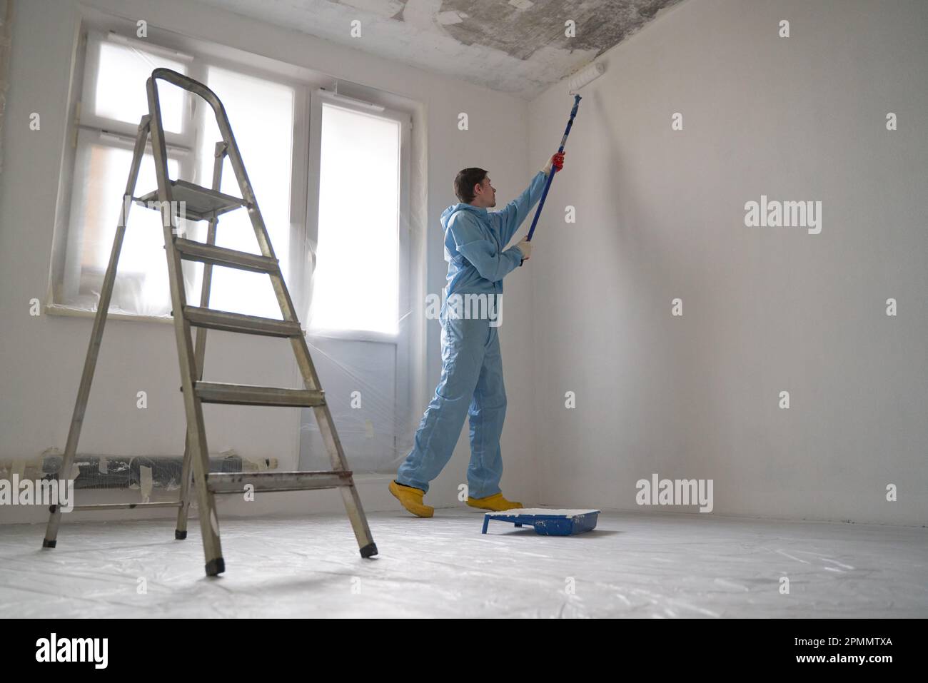 Man paints the ceiling with a roller. Concept of home makeover and ...