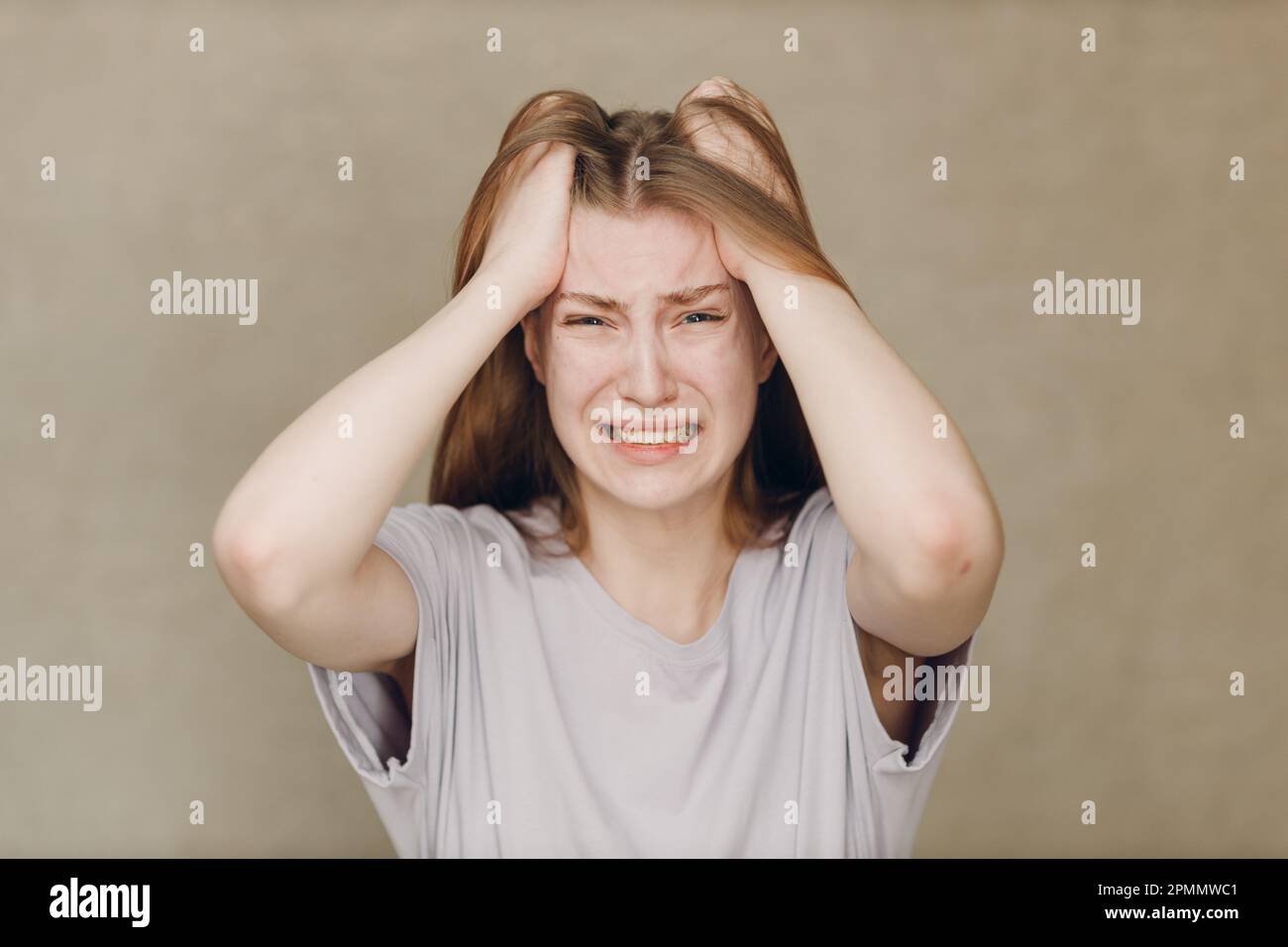 Portrait of young caucasian actress crying upset woman against beige ...